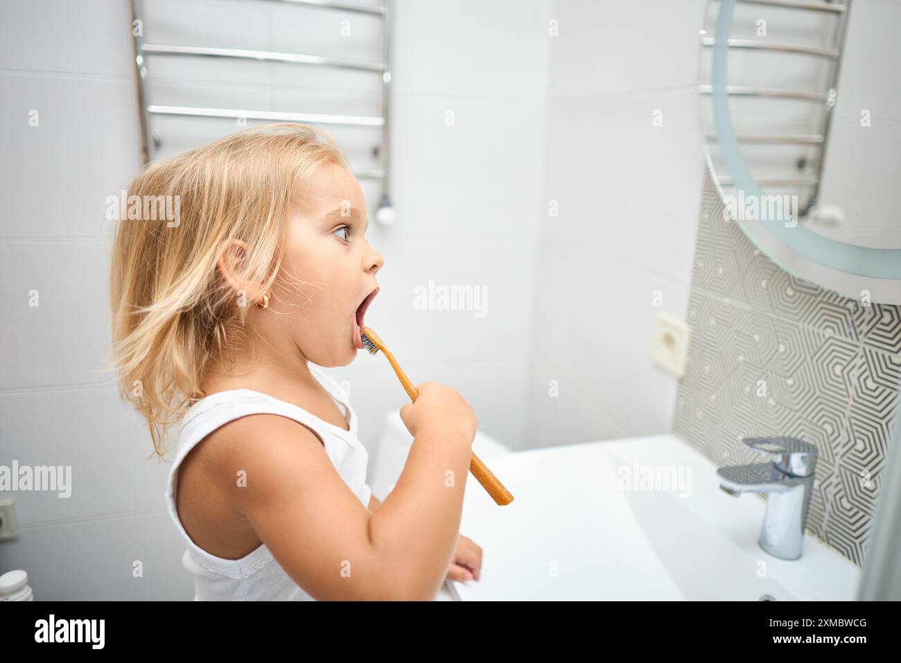 Morning routine, smiling happy child brushing teeth with toothbrush ...