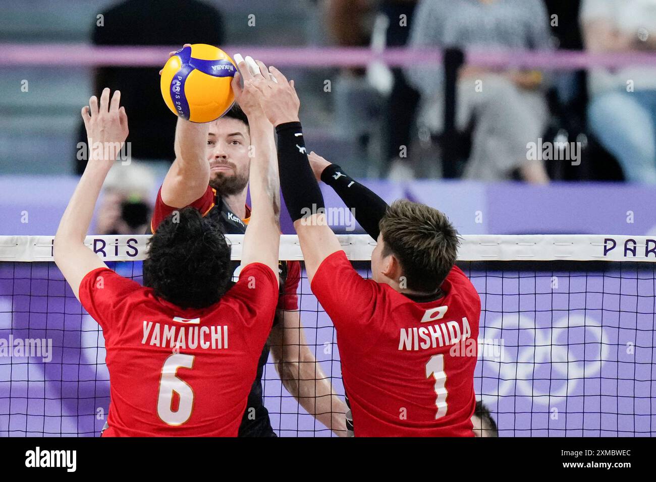 Tobias Brand, of Germany, center, spikes the ball as Akihiro Yamauchi ...