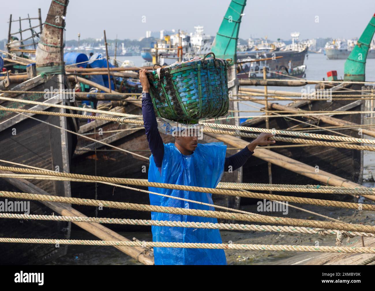 A bangladeshi porter carries a load from a trawler at the morning fish market, Chittagong ...