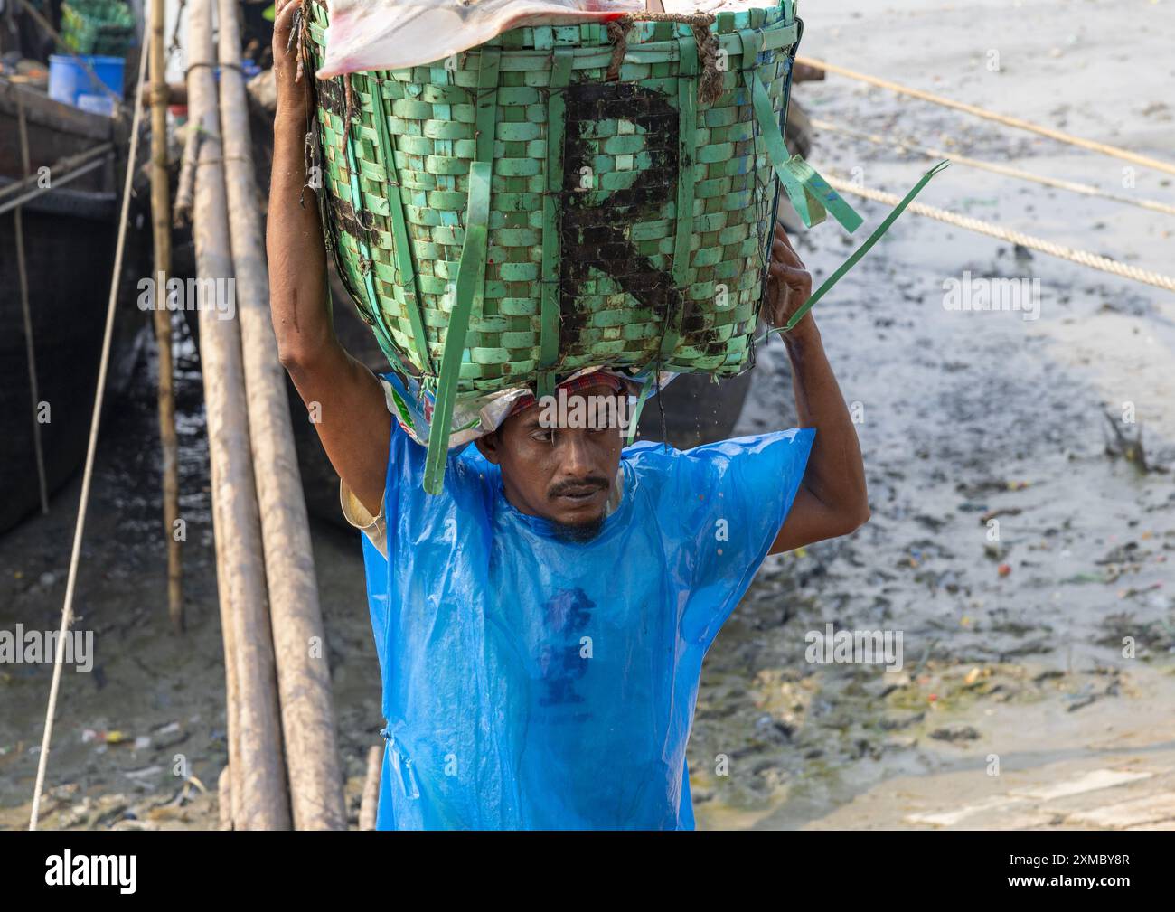 A bangladeshi porter carries a load at the morning fish market, Chittagong Division, Chittagong ...