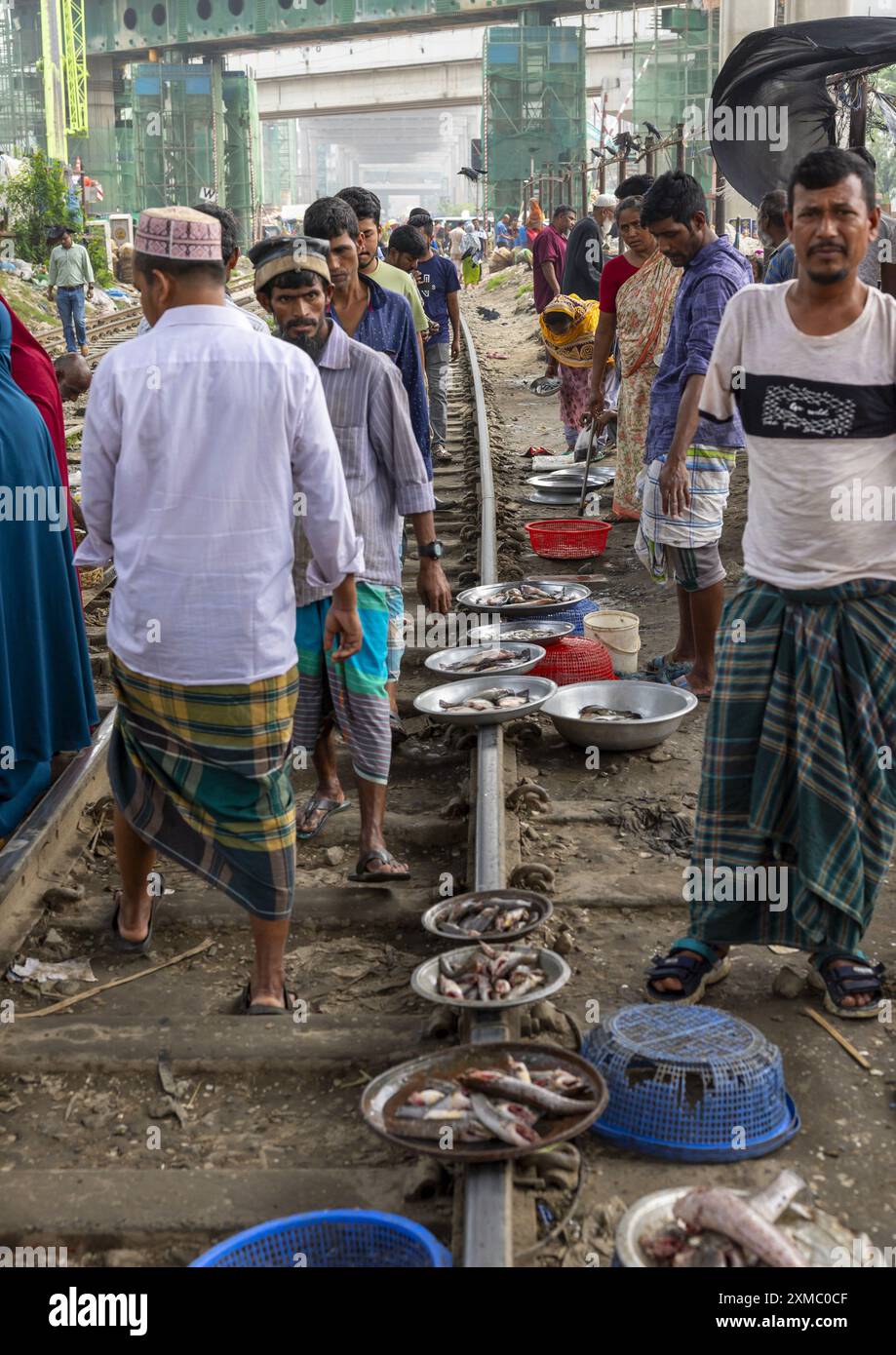 Bangladeshi men selling fishes along the railway track in Kawran bazar ...