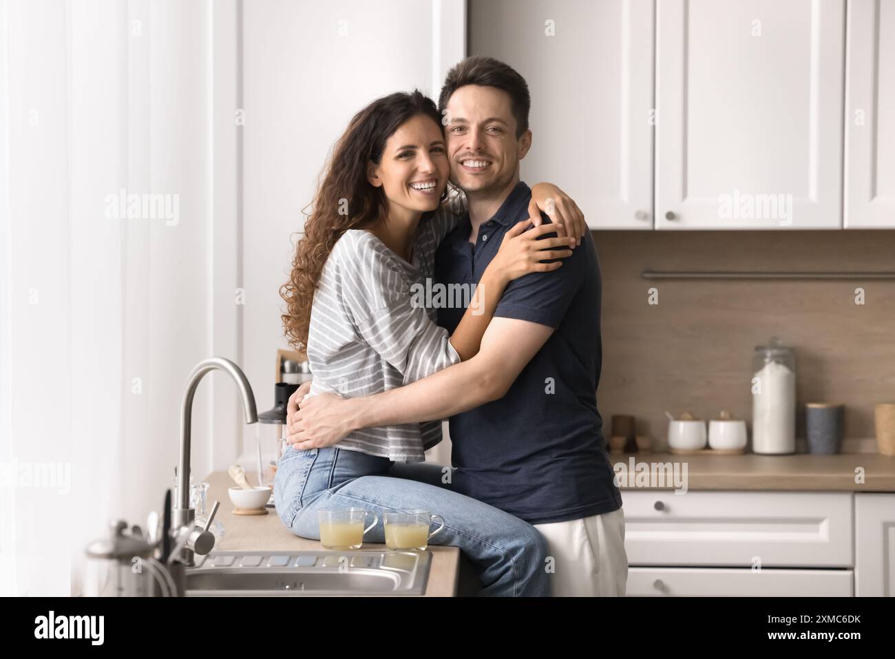 Beautiful married couple cuddling posing for camera in the kitchen ...