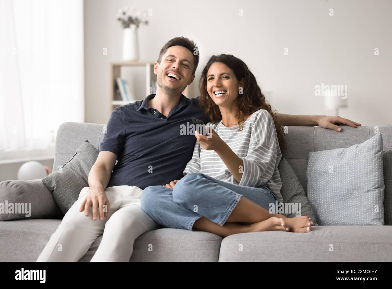 Laughing couple sit comfortably on sofa, engrossed in watching TV Stock Photo - Alamy