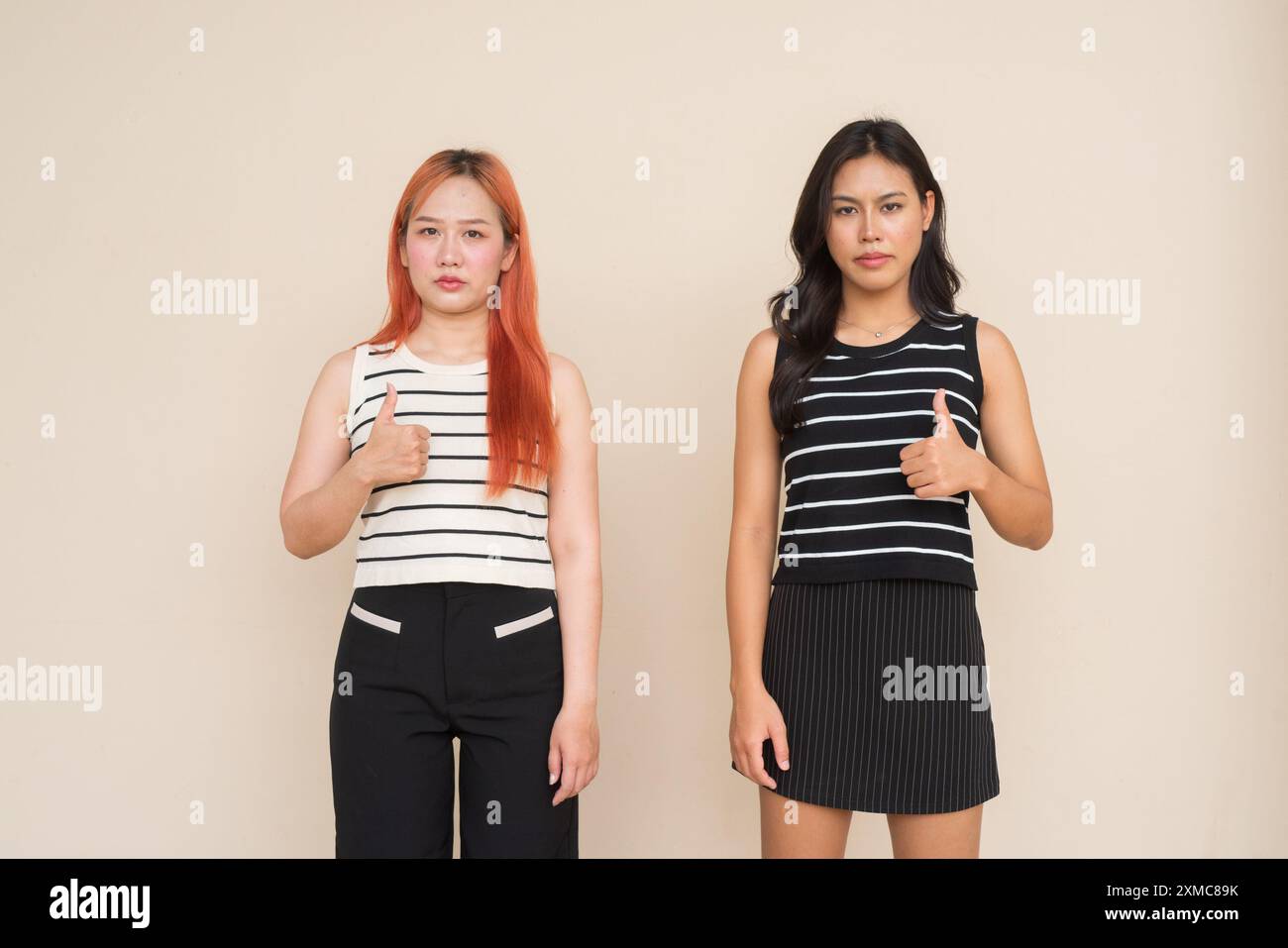 Portrait of Two Beautiful Asian Woman Giving Thumbs Up Outdoors Against Plain Background Stock ...