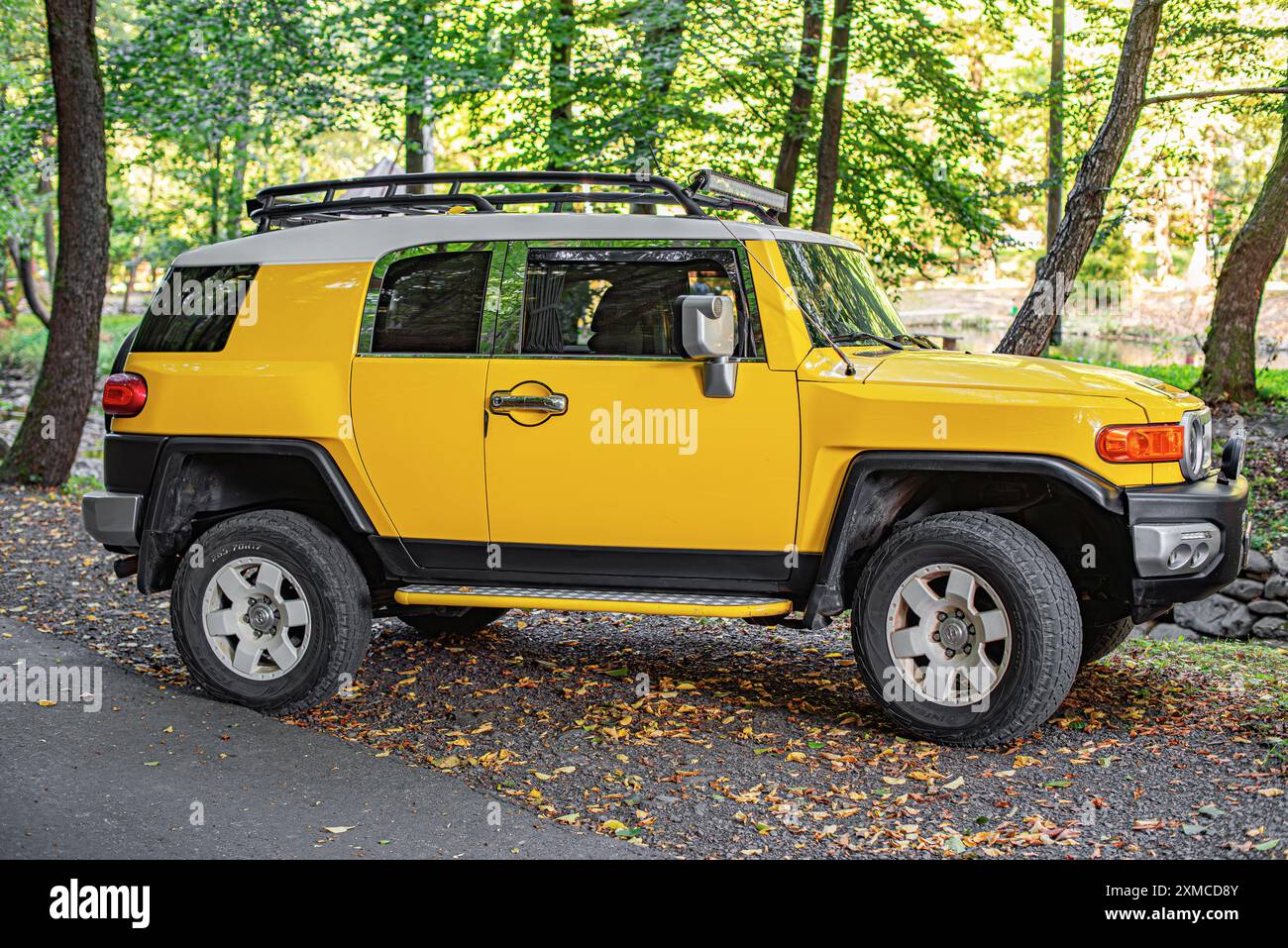 Yellow Toyota FJ Cruiser parked against a backdrop of trees Stock Photo ...