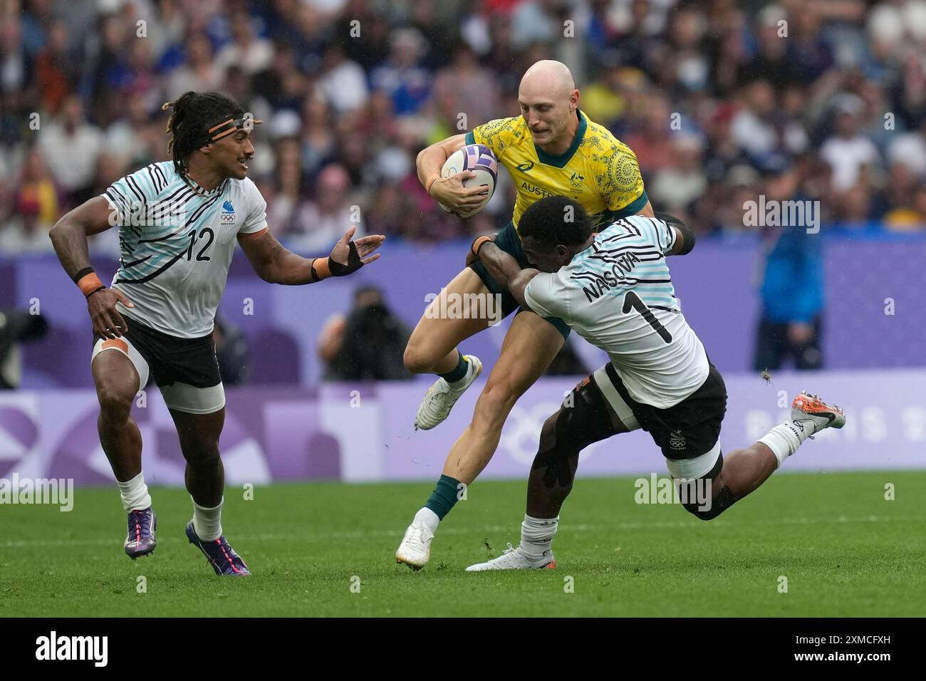 Australia's James Turner, centre, is tackled by Fiji's Joji Nasova ...