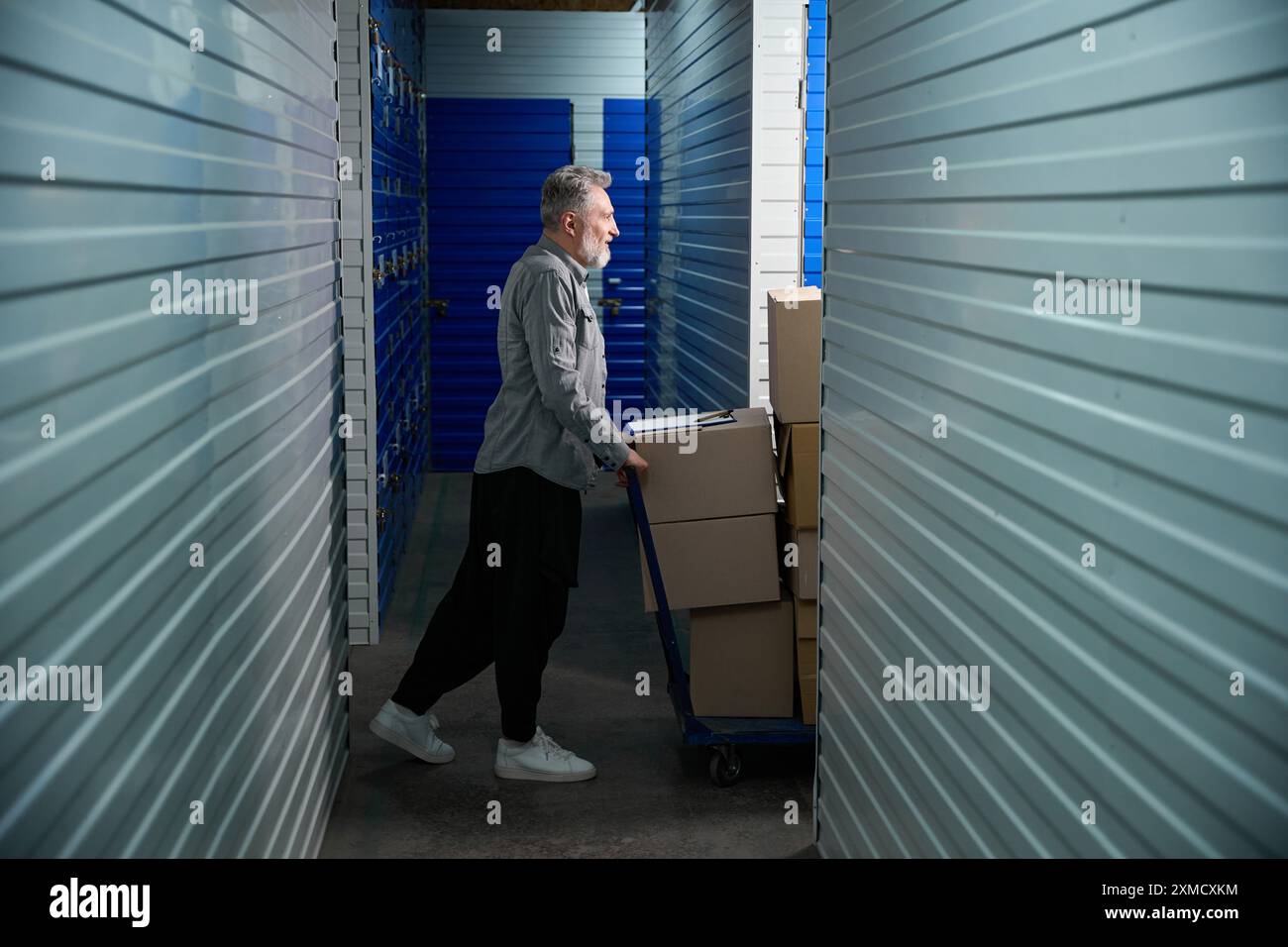 Man carrying large trolley filled with stacked boxes Stock Photo - Alamy