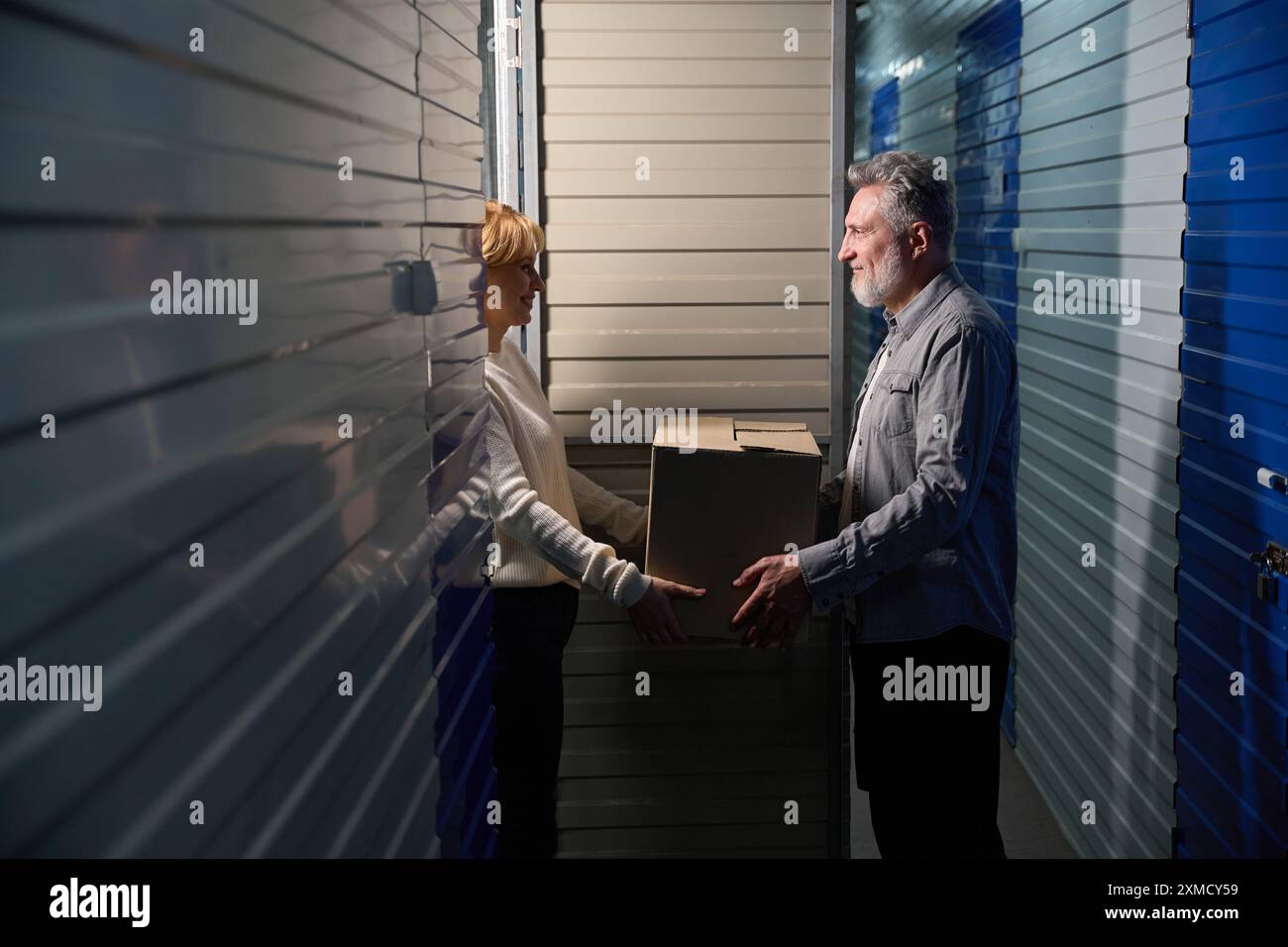 Male standing in warehouse hands over boxes to lady Stock Photo - Alamy