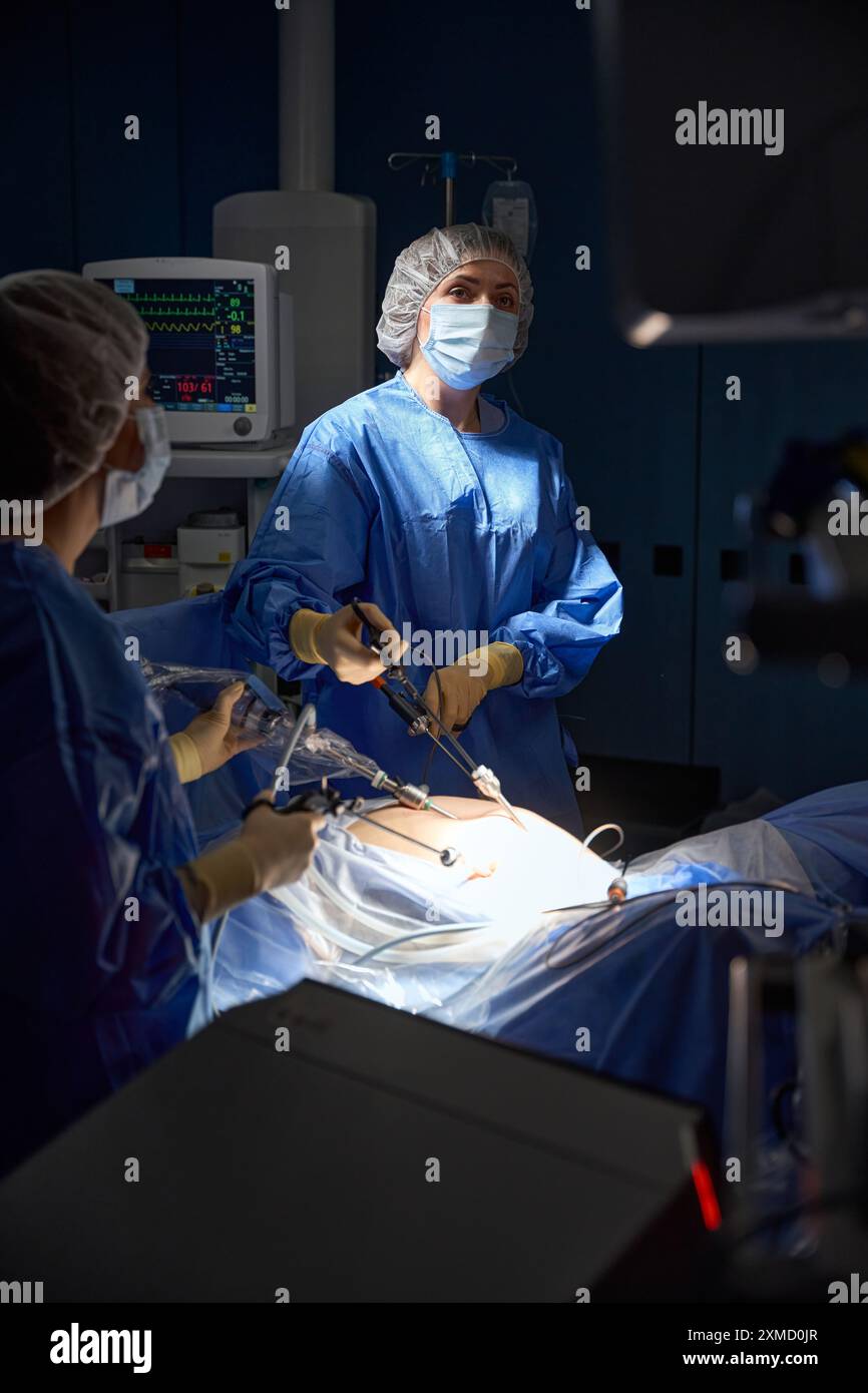 Medical team performing surgery in dark operating room in hospital ...