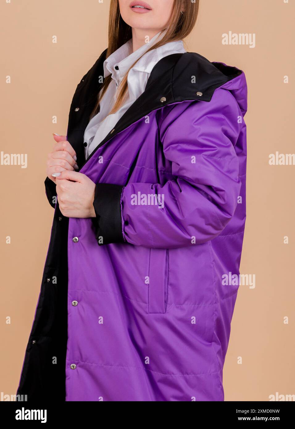 A woman models a stylish purple winter coat over a white shirt, posing ...