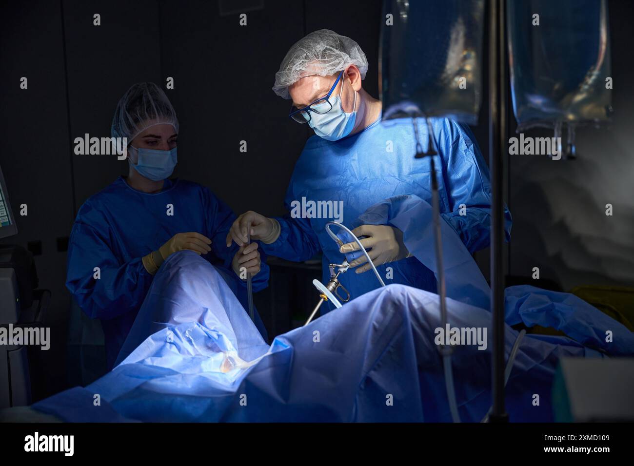 Male gynecologist with woman assistant in mask and hair cap with ...