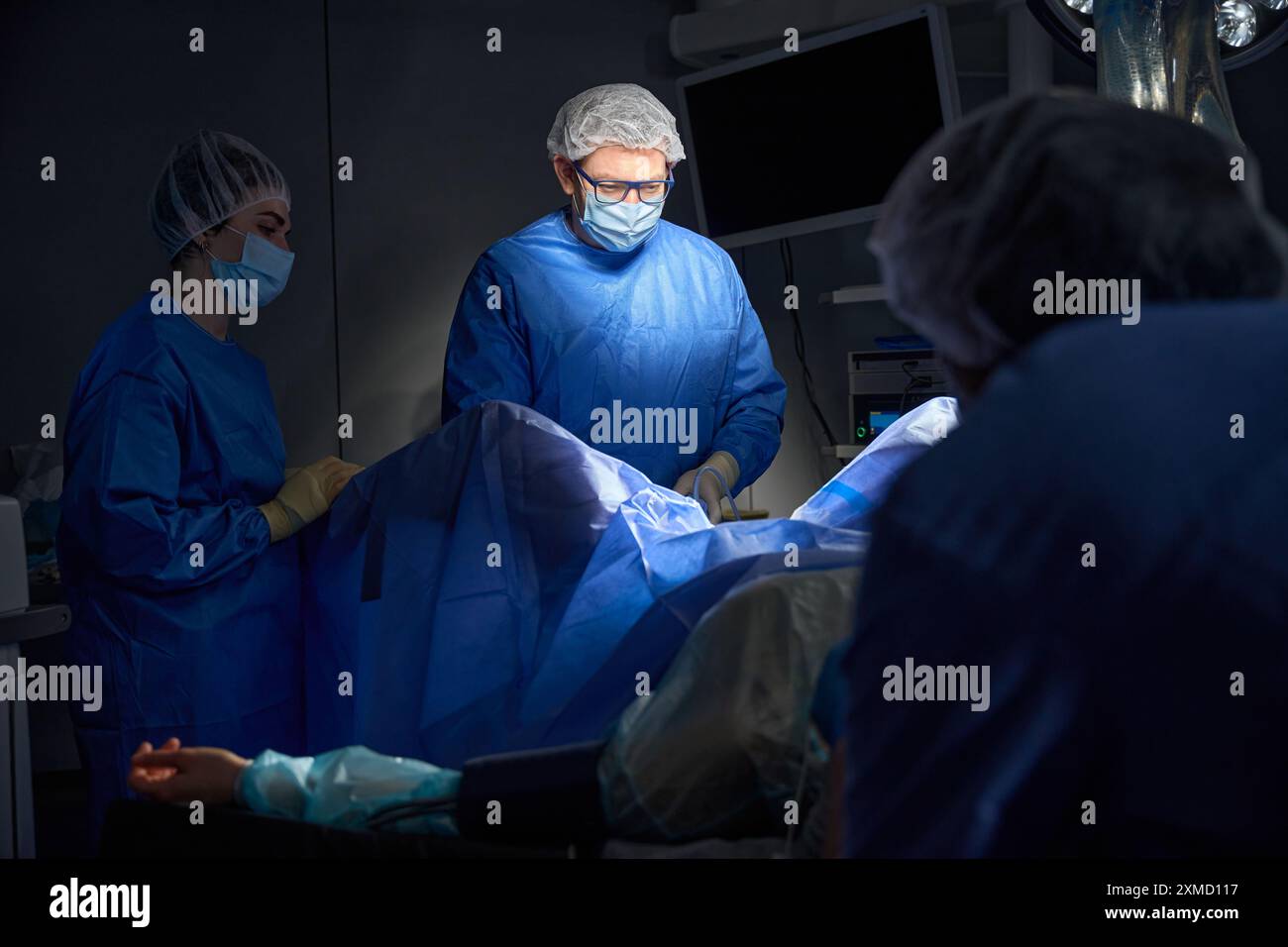 Female and male surgeons operating on patient in operating theatre ...
