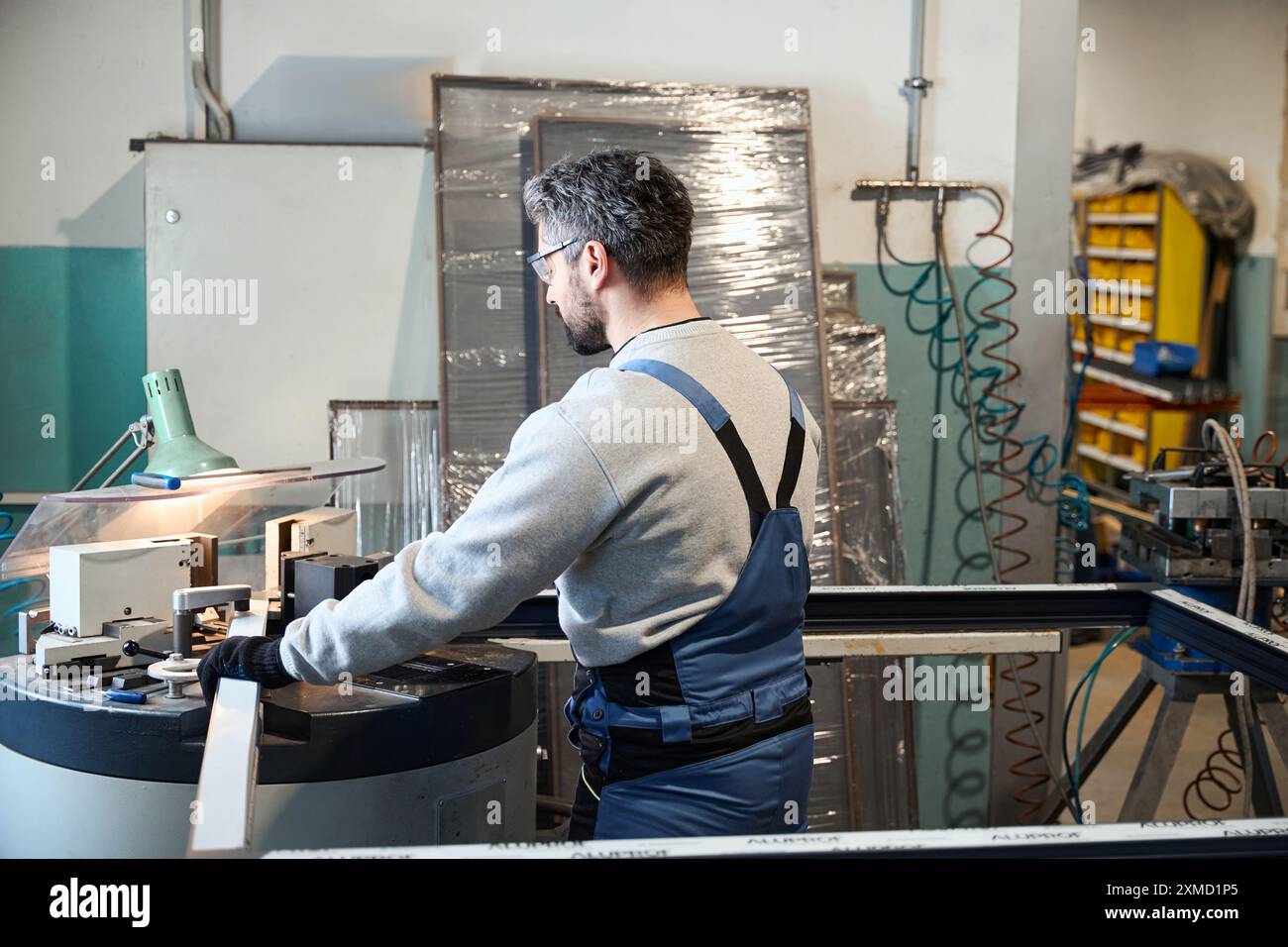 Specialist in work overalls works on special machine with aluminum ...