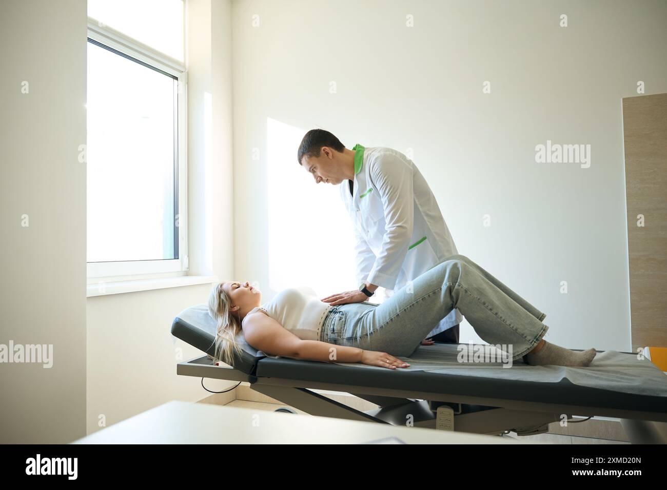 Healthcare professional performing abdominal palpation of female ...