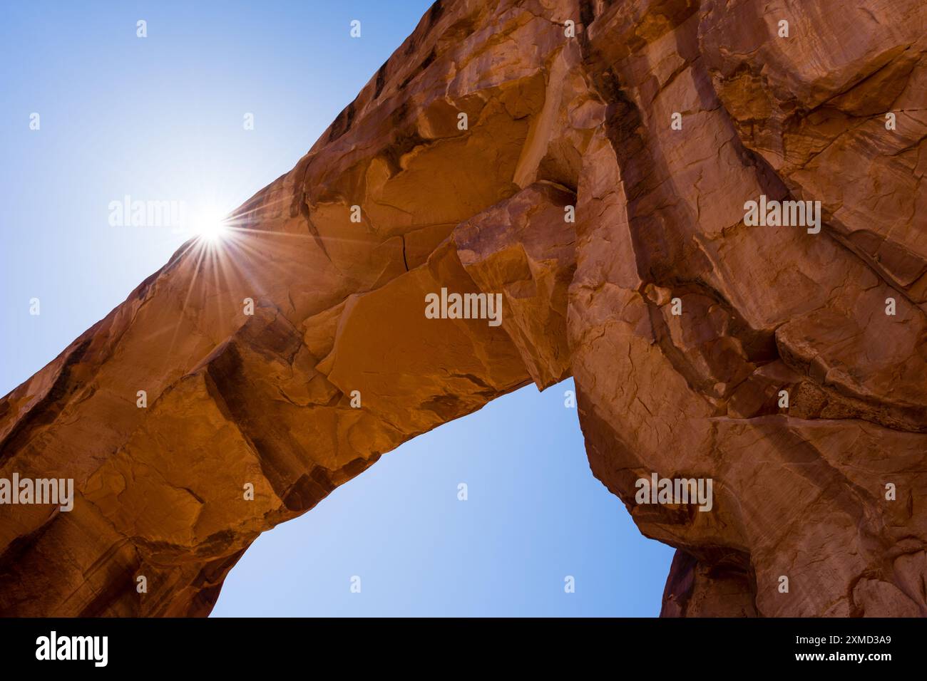 Sun peeking from behind the Pine Tree Arch in Arches National Park ...