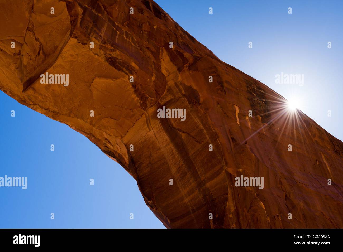 Sun peeking from behind the Pine Tree Arch in Arches National Park ...