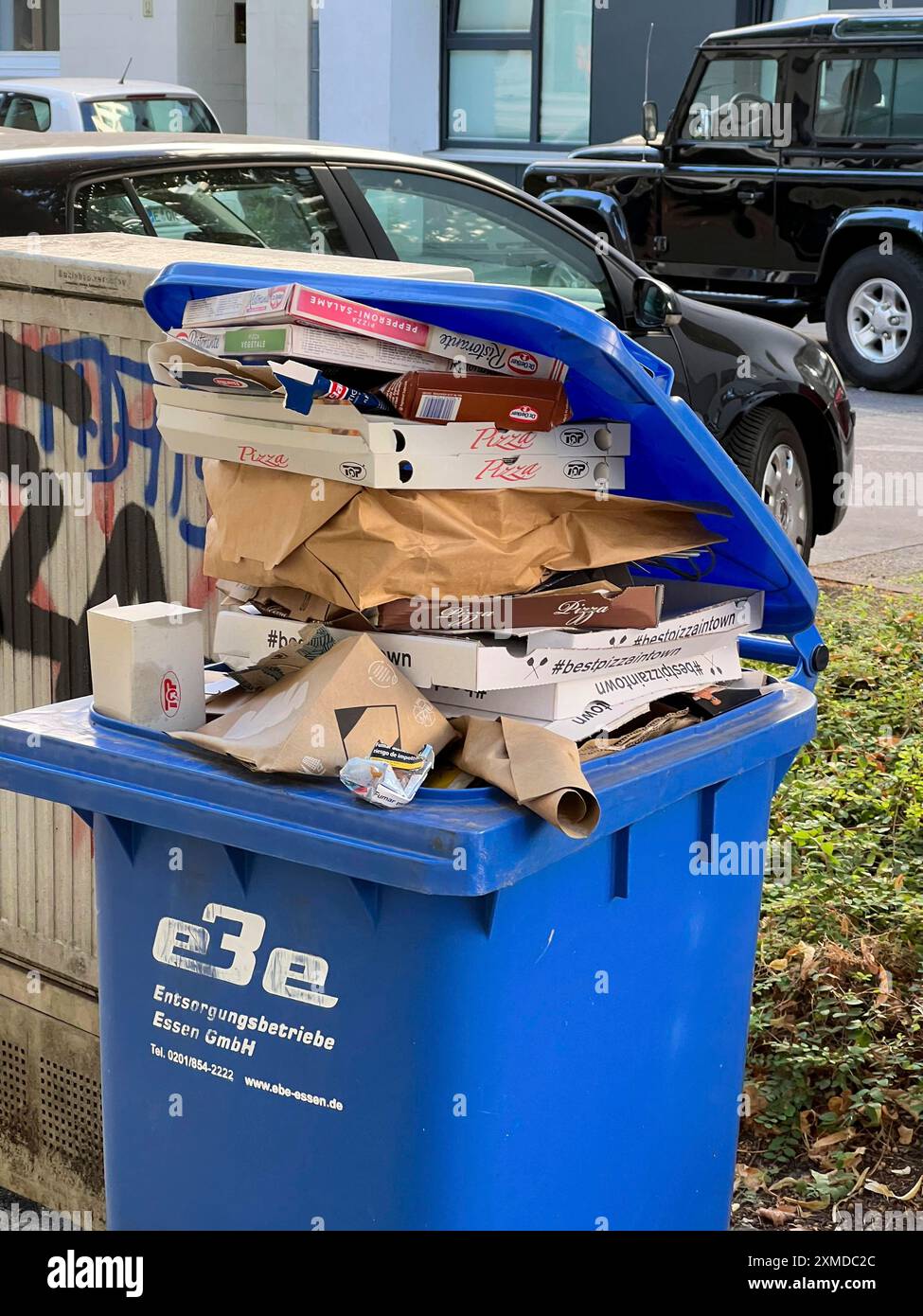 Overflowing waste paper bin, standing on a pavement, waiting to be ...