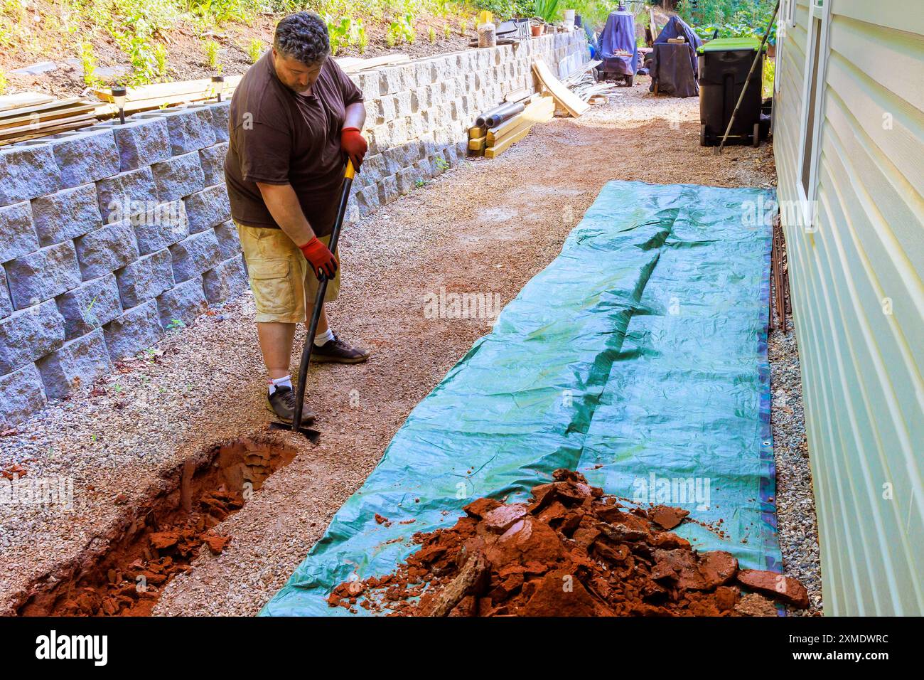 At construction site, worker digs trench to lay drainage system that ...