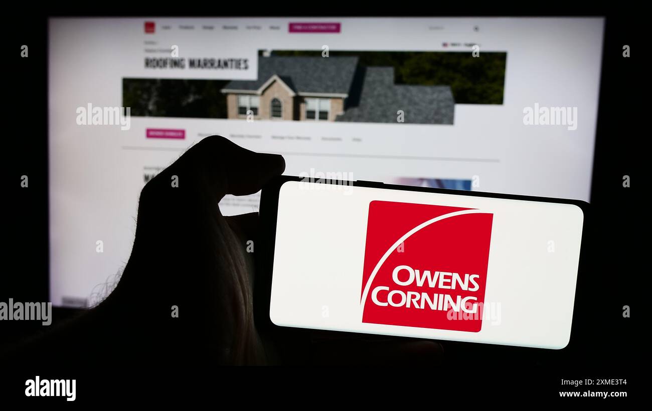 Person holding smartphone with logo of US building materials company ...