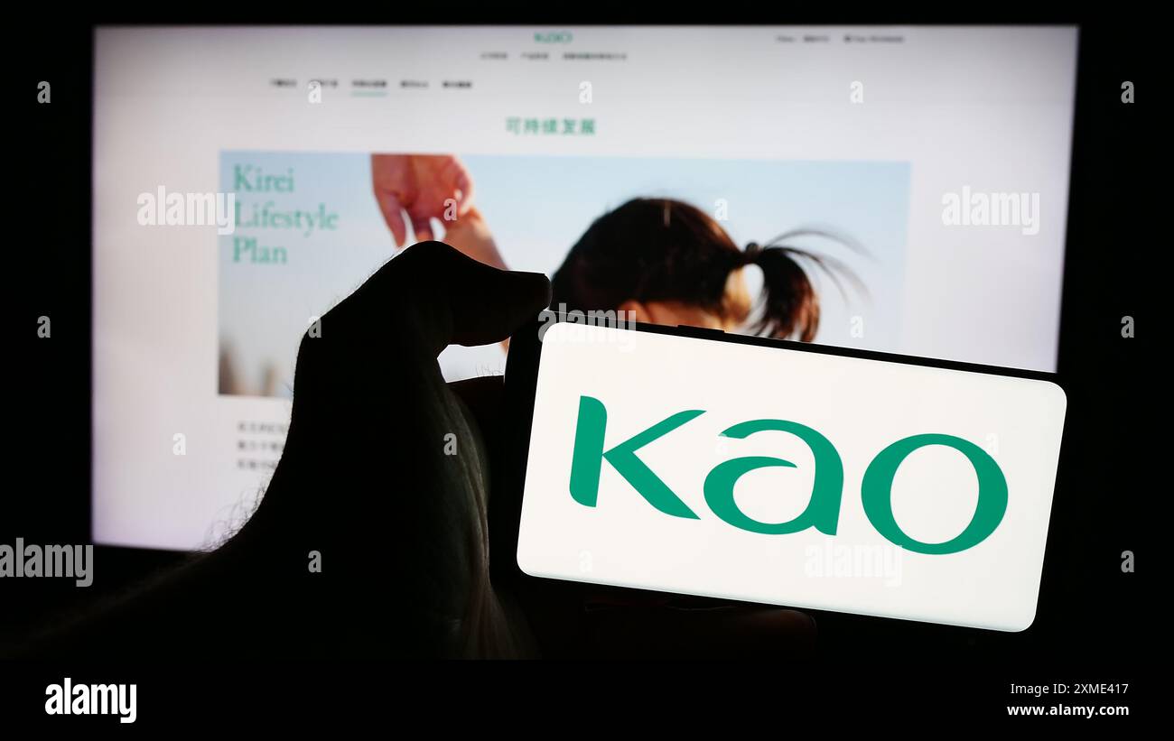 Person holding mobile phone with logo of Japanese chemical company Kao ...