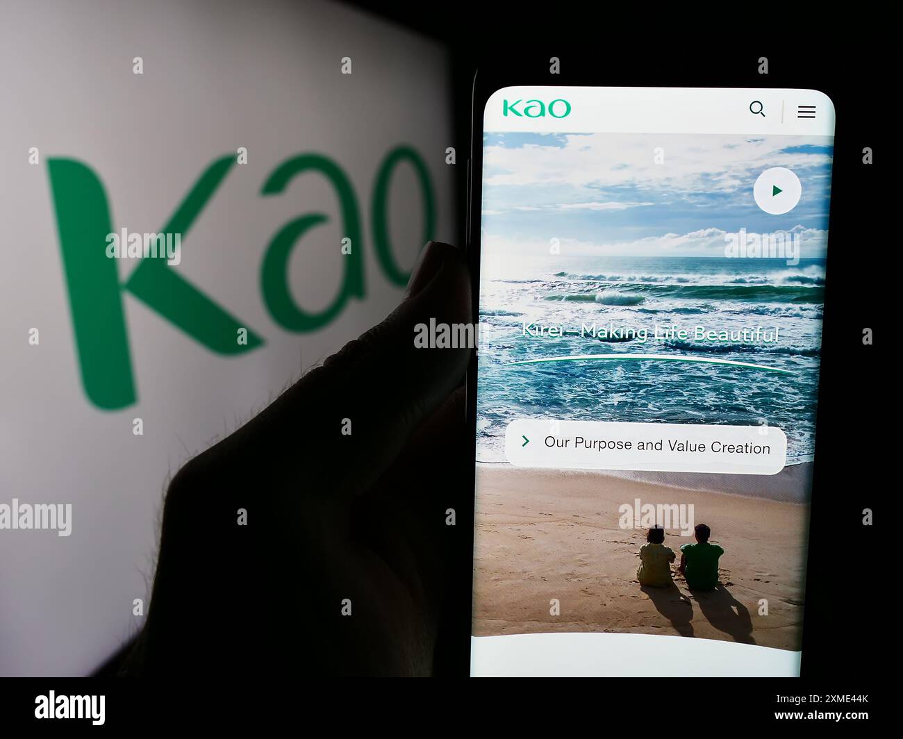 Person holding cellphone with webpage of Japanese chemical company Kao ...