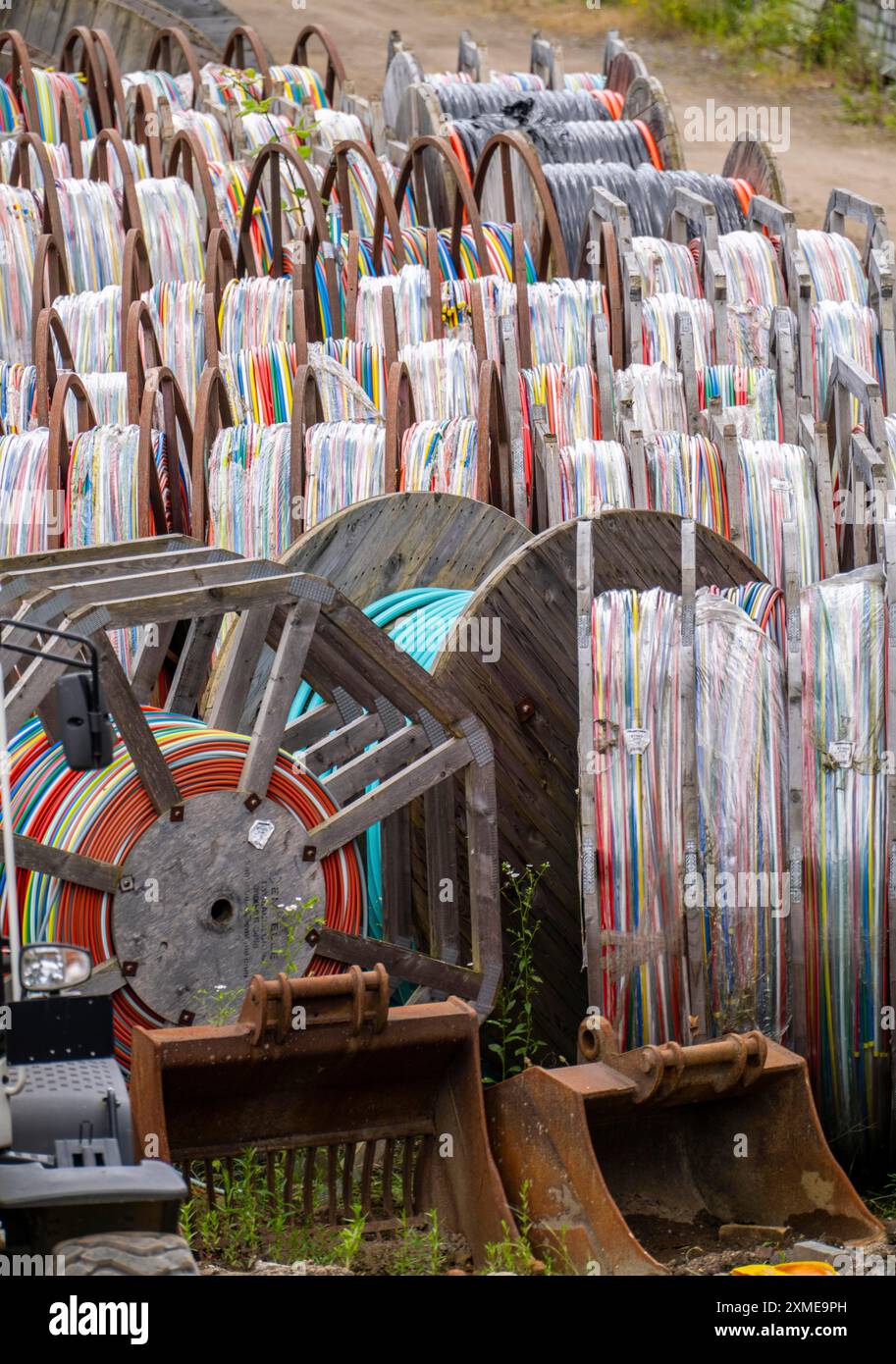 Cable drums with conduits for fibre optic cables, in a storage yard ...