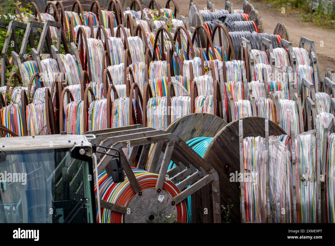 Cable drums with conduits for fibre optic cables, in a storage yard ...