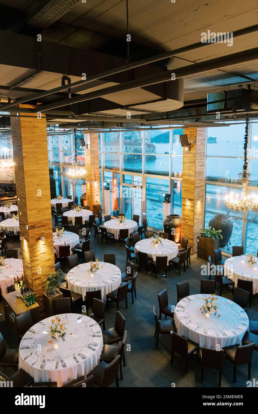 Large restaurant with columns and high ceilings with served round ...