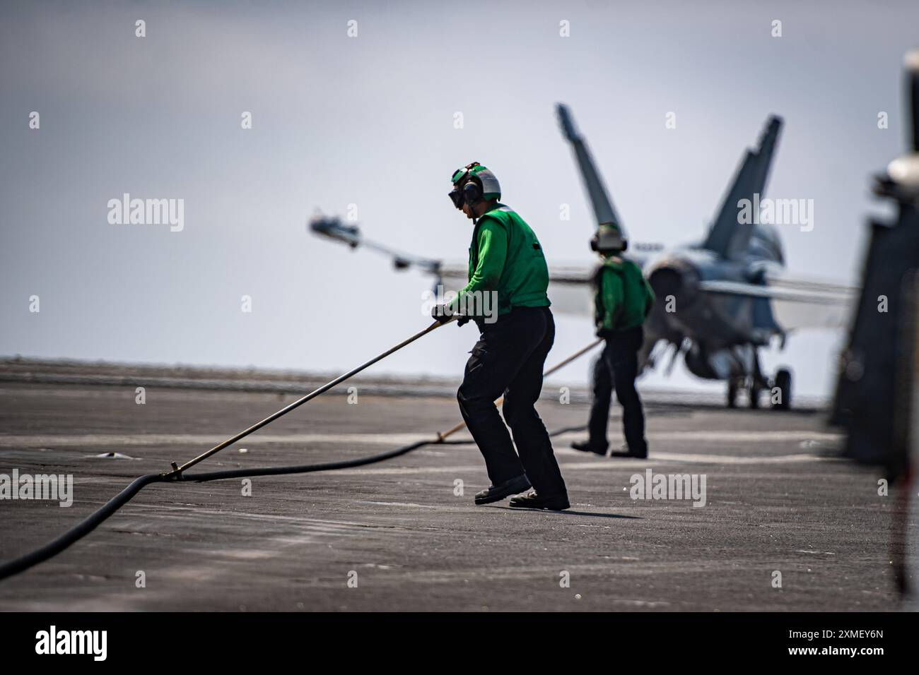Sailors guide an arresting wire after an arrested landing on the flight ...