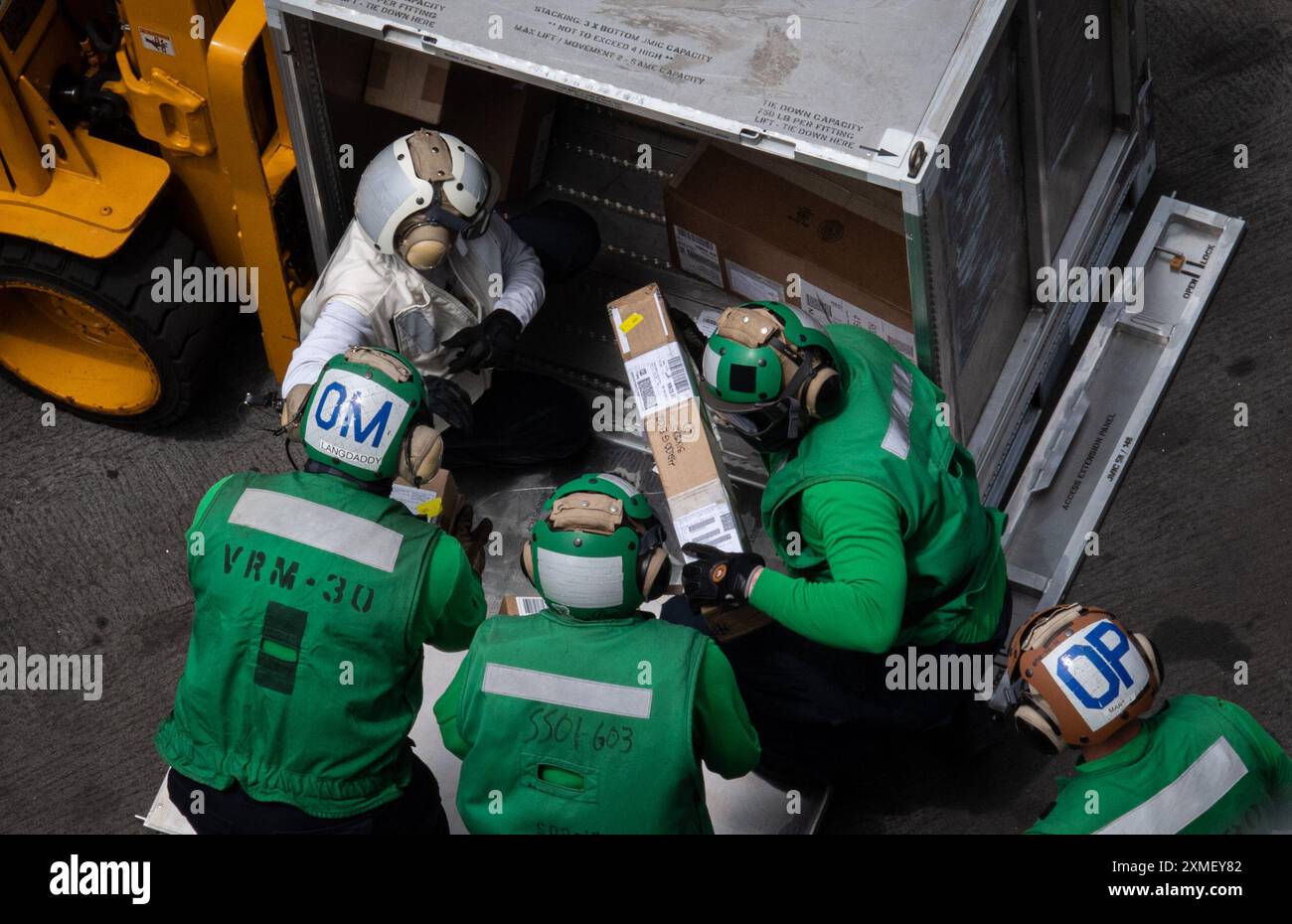 Sailors unload and sort mail on the flight deck of the aircraft carrier ...