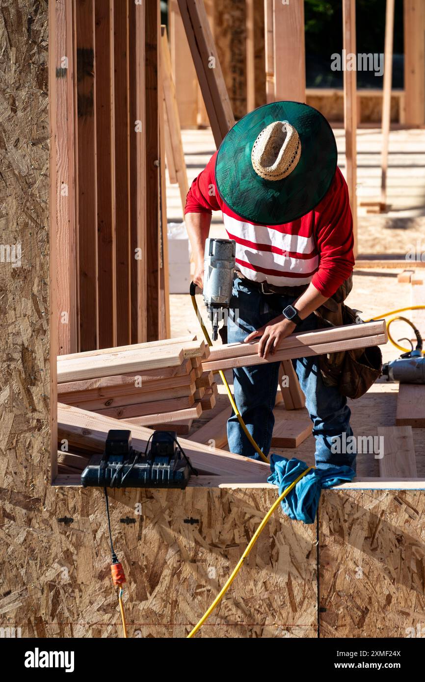 Construction worker in toolbelt and sun hat working with a pneumatic ...