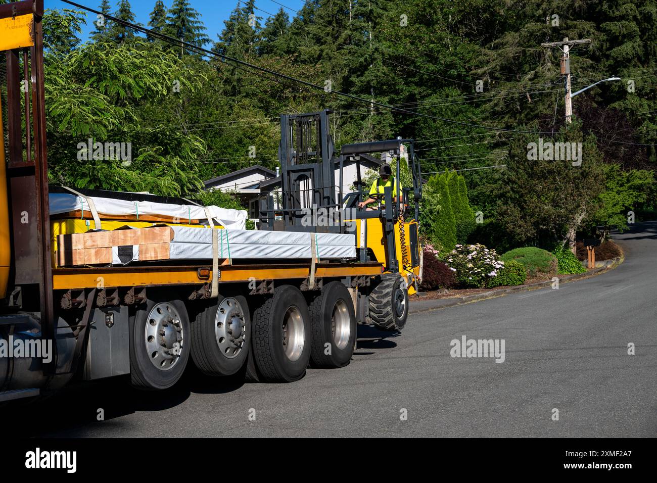 Forklift being attached to commercial flatbed lumber delivery truck in ...
