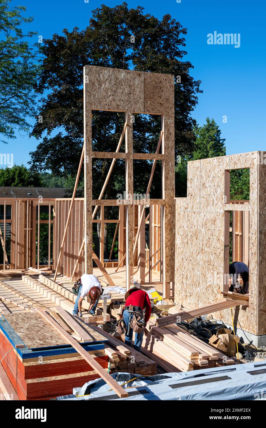 Construction work crew building a new house in a residential neighborhood, wood framing started ...