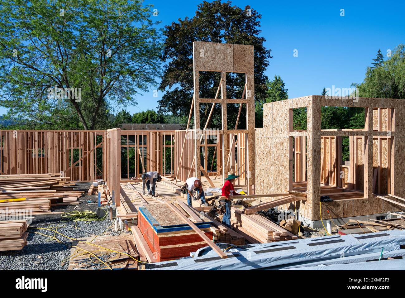 Construction work crew building a new house in a residential neighborhood, wood framing started ...