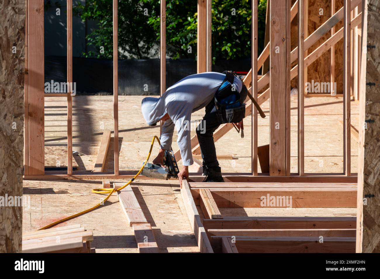 Construction worker in toolbelt working with a pneumatic nail gun on ...