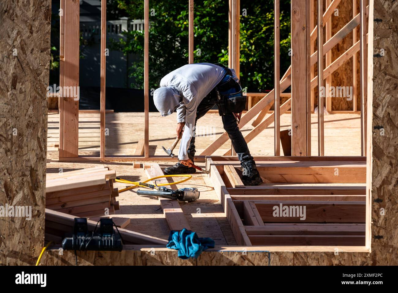 Construction worker in toolbelt working with a hammer and pry bar on ...