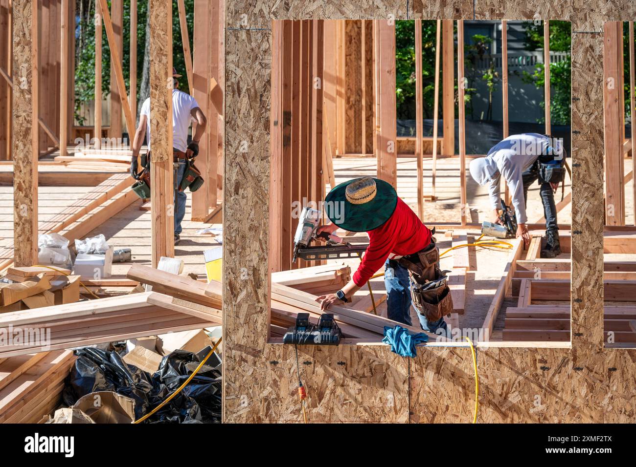 Construction work crew building a new house in a residential neighborhood, wood framing started ...
