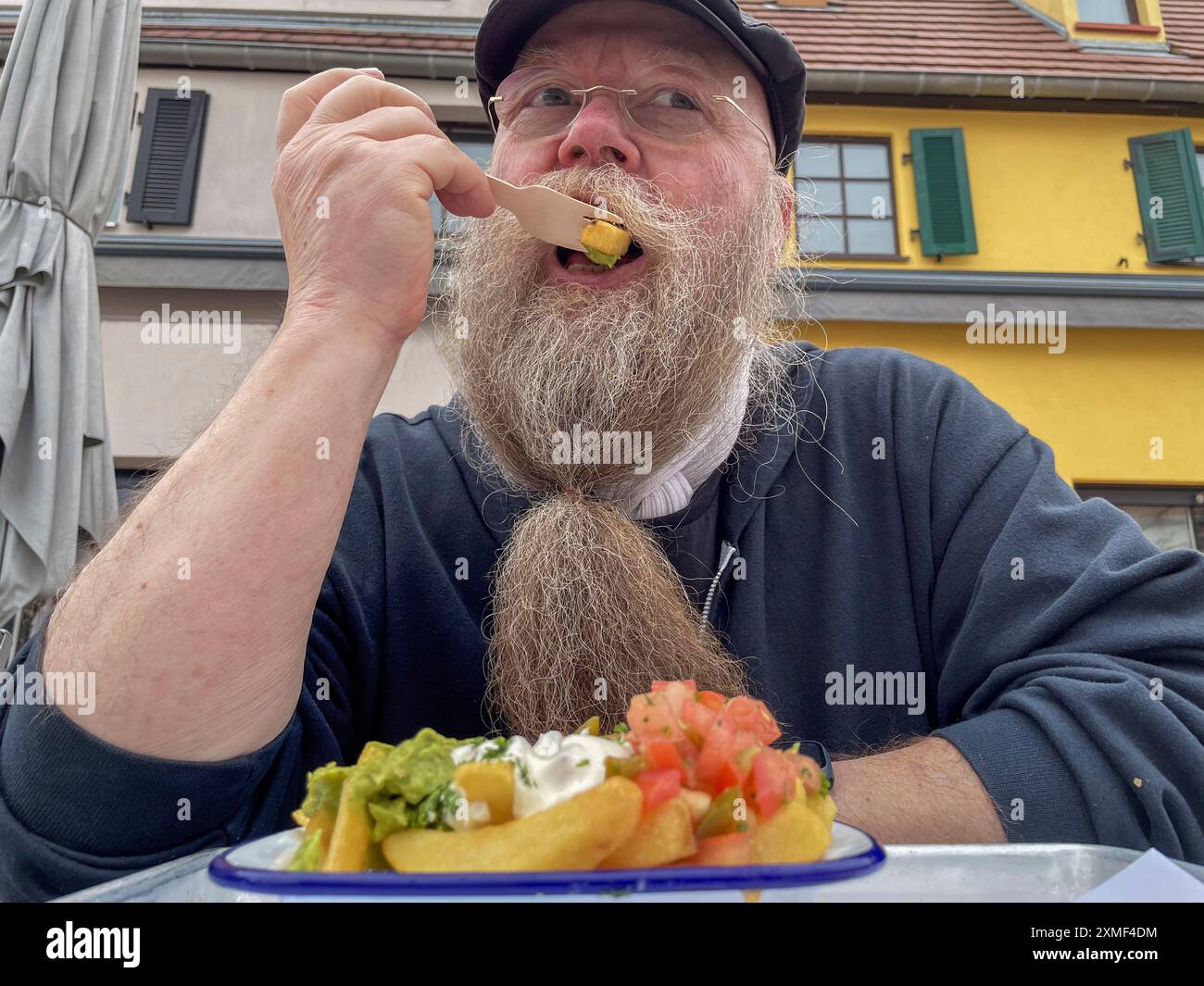 Mann mit langem Bart isst eine Schale Kartoffel Schnitze, Pommes, mit ...