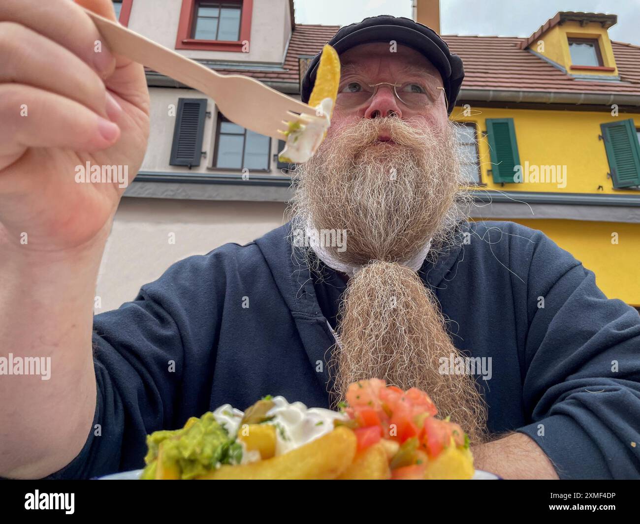 Mann mit langem Bart isst eine Schale Kartoffel Schnitze, Pommes, mit ...