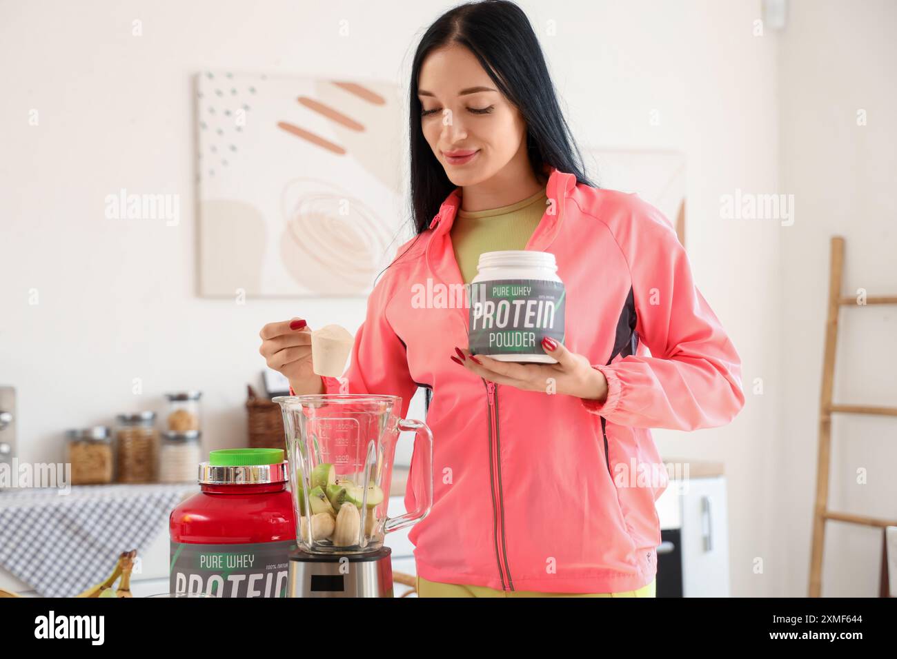 Sporty young woman with blender making protein shake in kitchen Stock ...