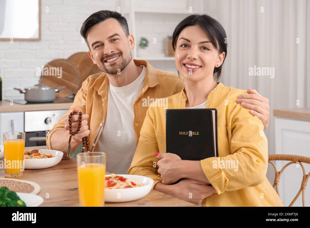 Religious couple with Holy Bible having dinner at table in kitchen ...