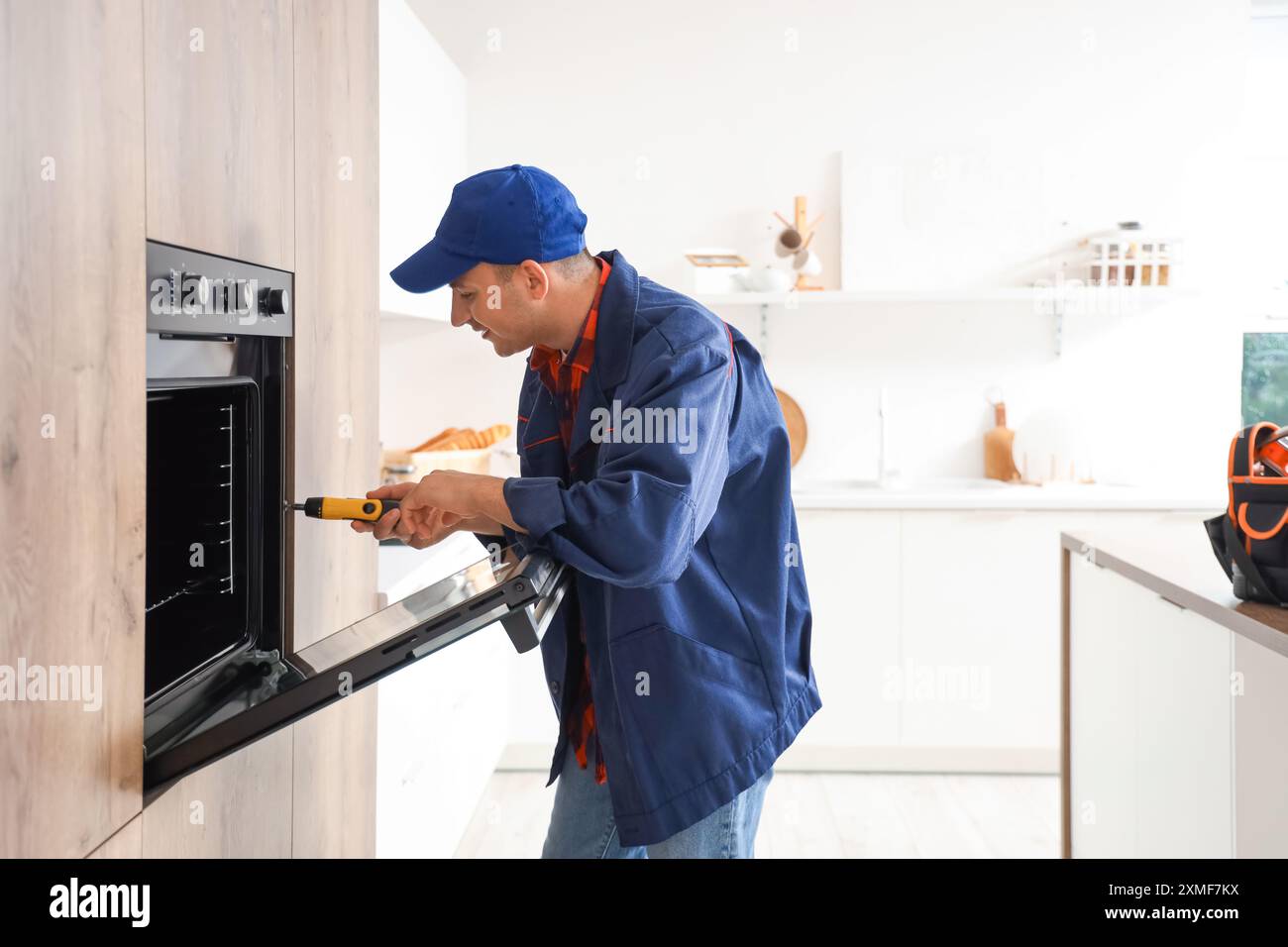 Male technician repairing electric oven in kitchen Stock Photo - Alamy