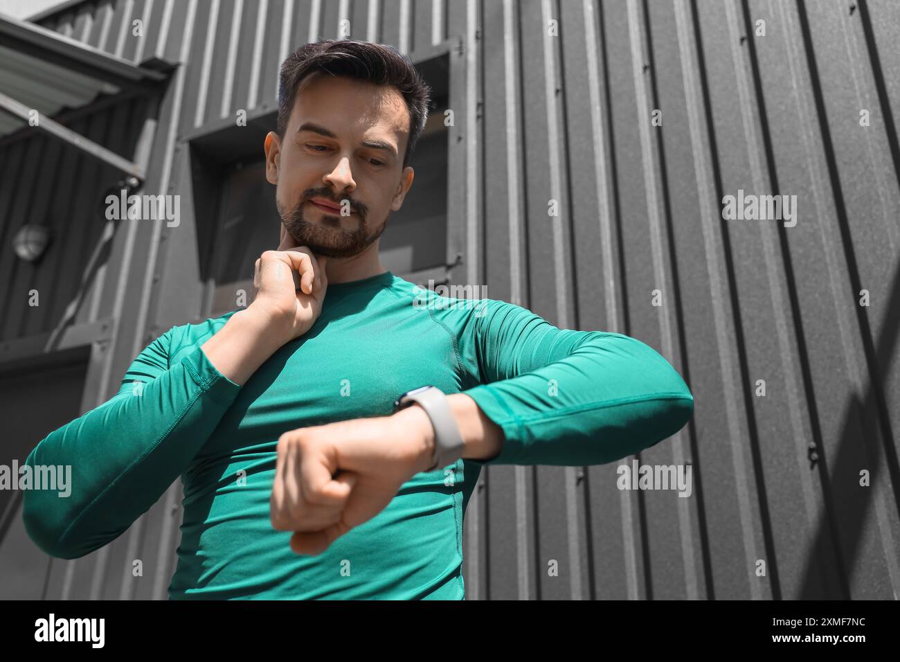 Sporty young man with smartwatch checking his pulse on street Stock ...