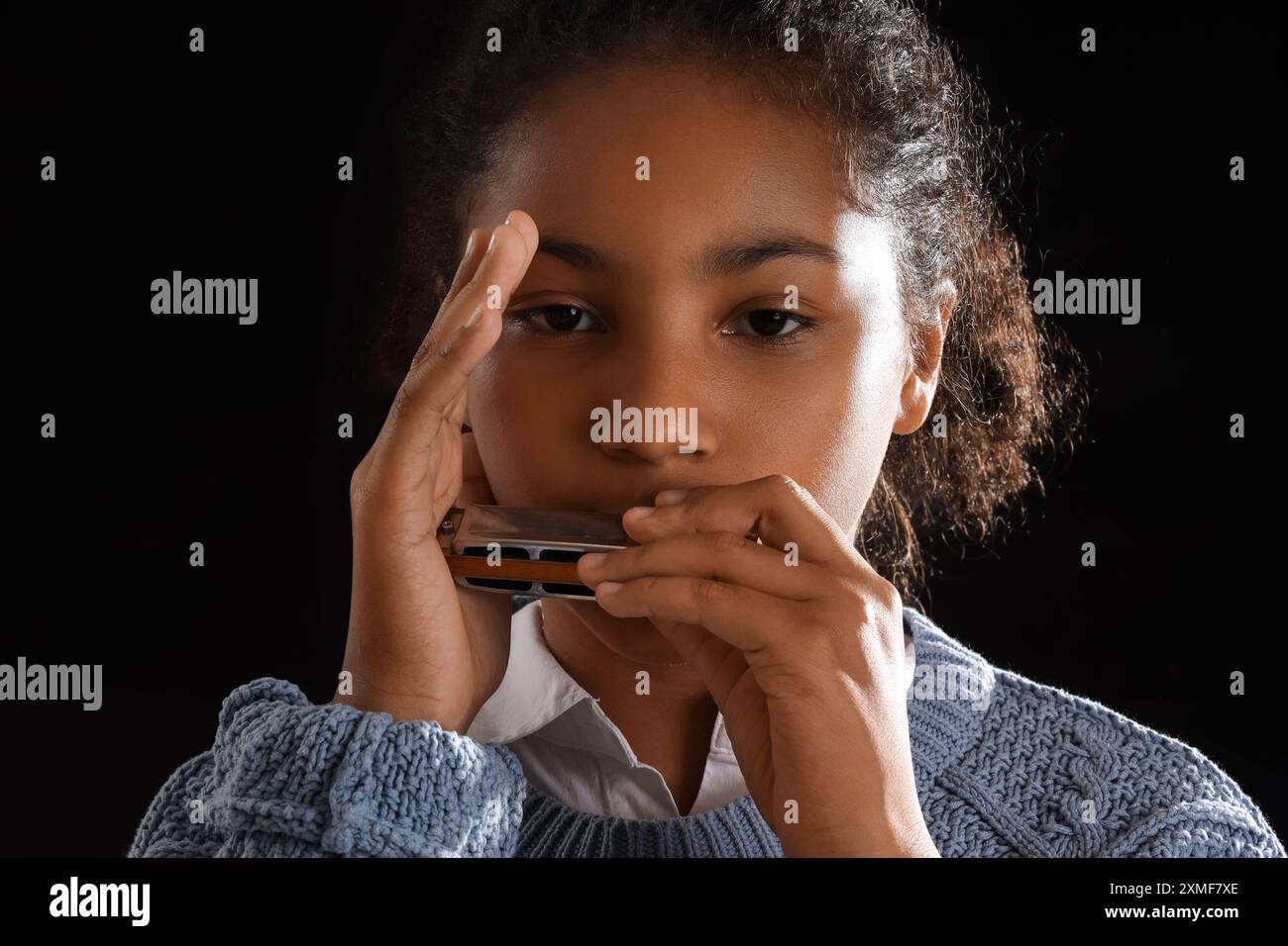 Little African-American girl playing harmonica on dark background, closeup Stock Photo - Alamy