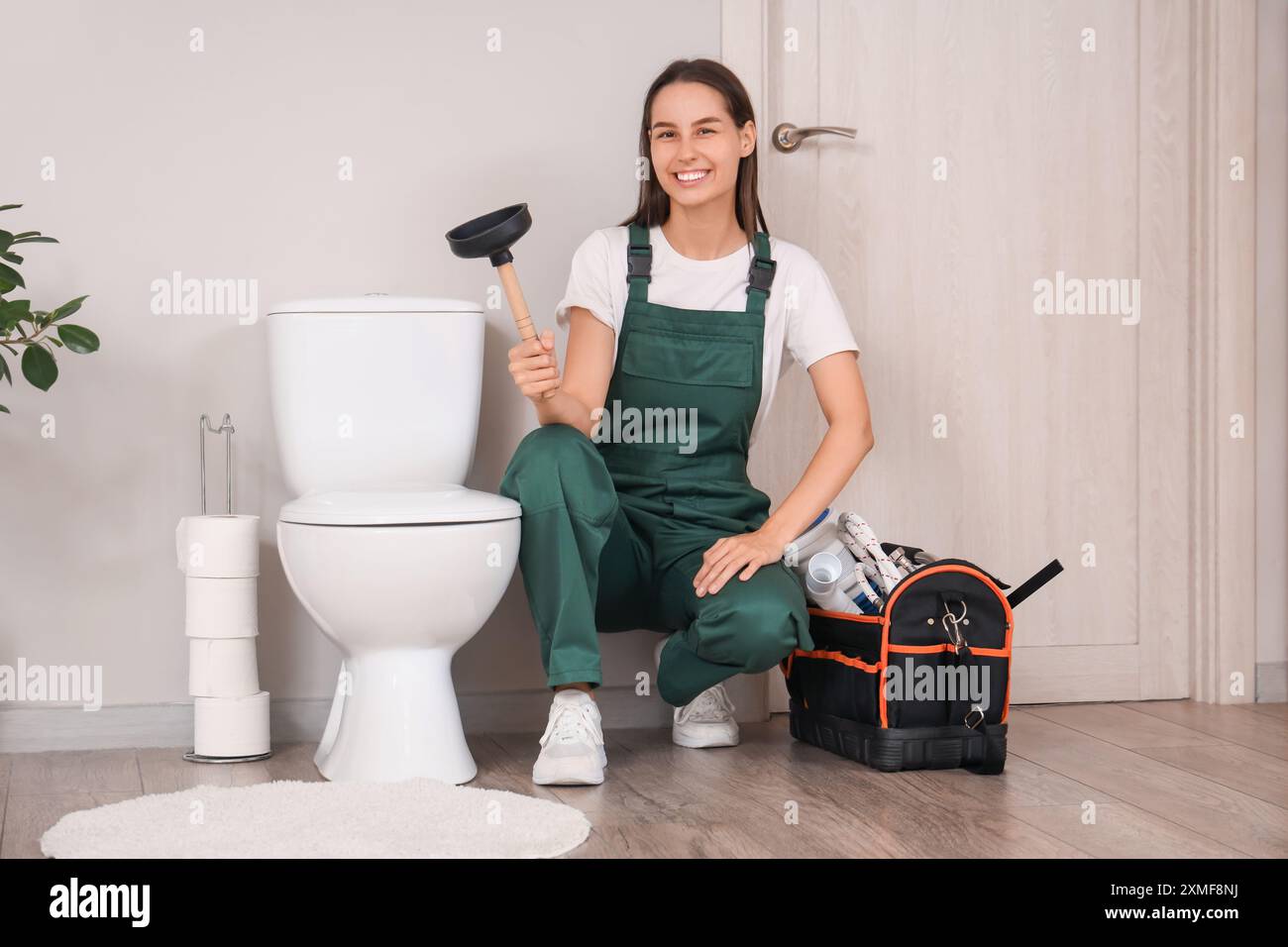 Female plumber with plunger near toilet bowl in restroom Stock Photo ...