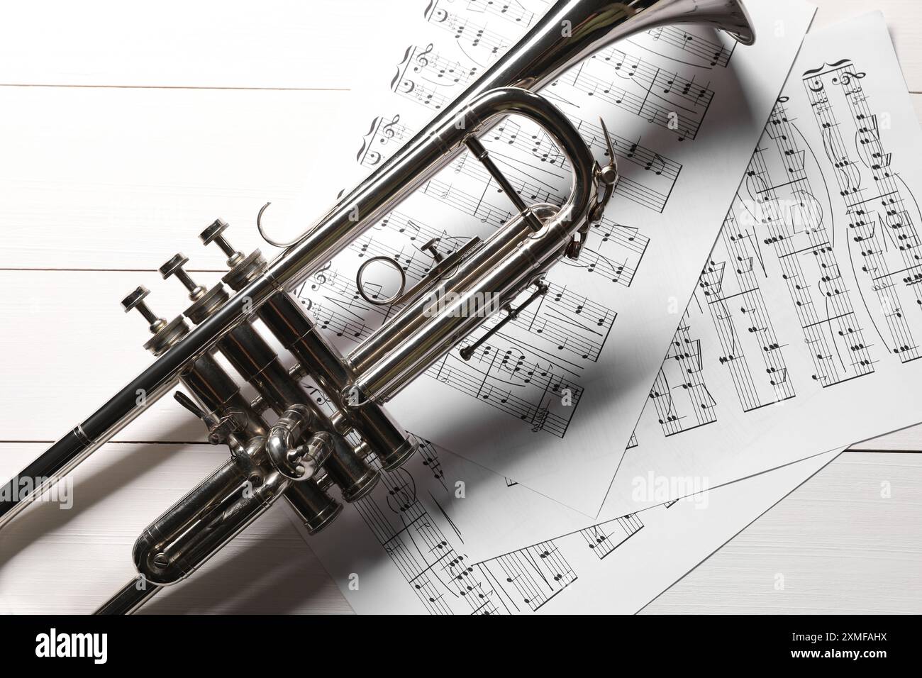 Trumpet and music sheet papers with notes on white wooden table, flat ...