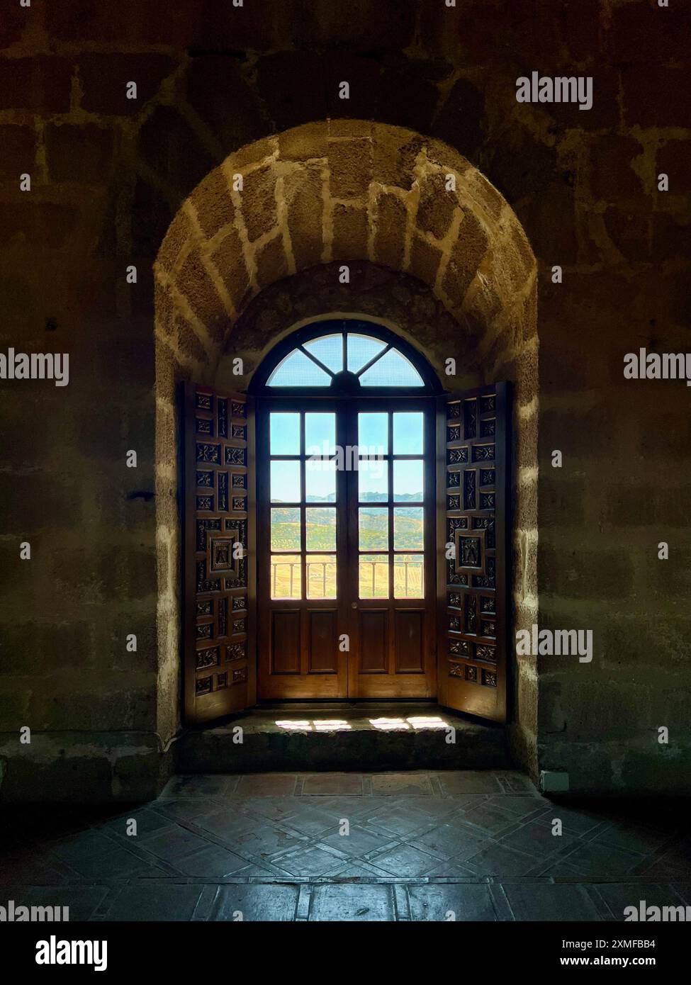 An arched window inside the Puente Nuevo looks out into the valley ...