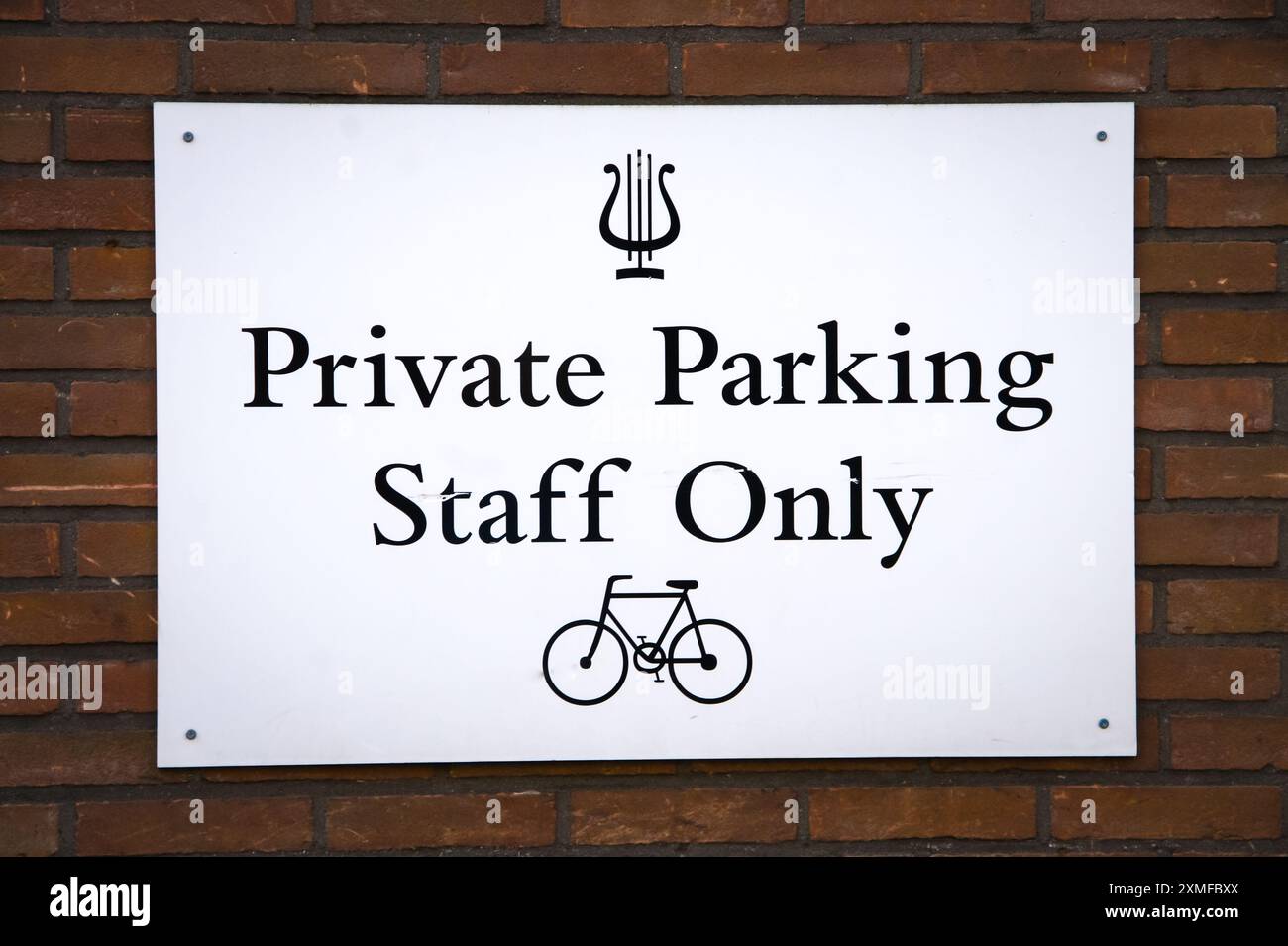 A white sign with red text "Private parking staff only" and a black ...