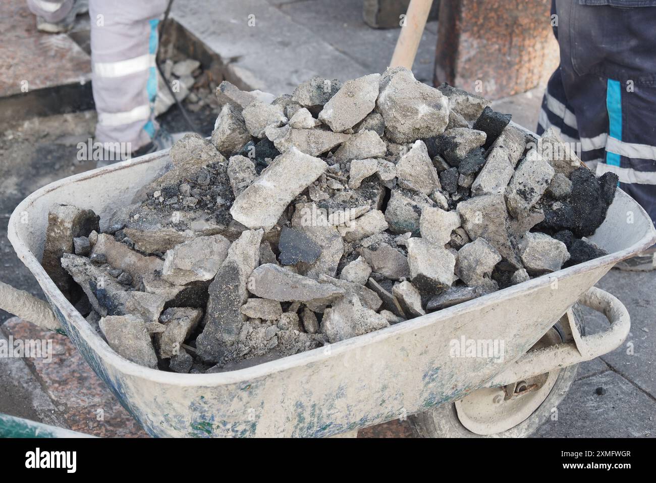 A group of construction workers moving a wheelbarrow loaded with rubble ...