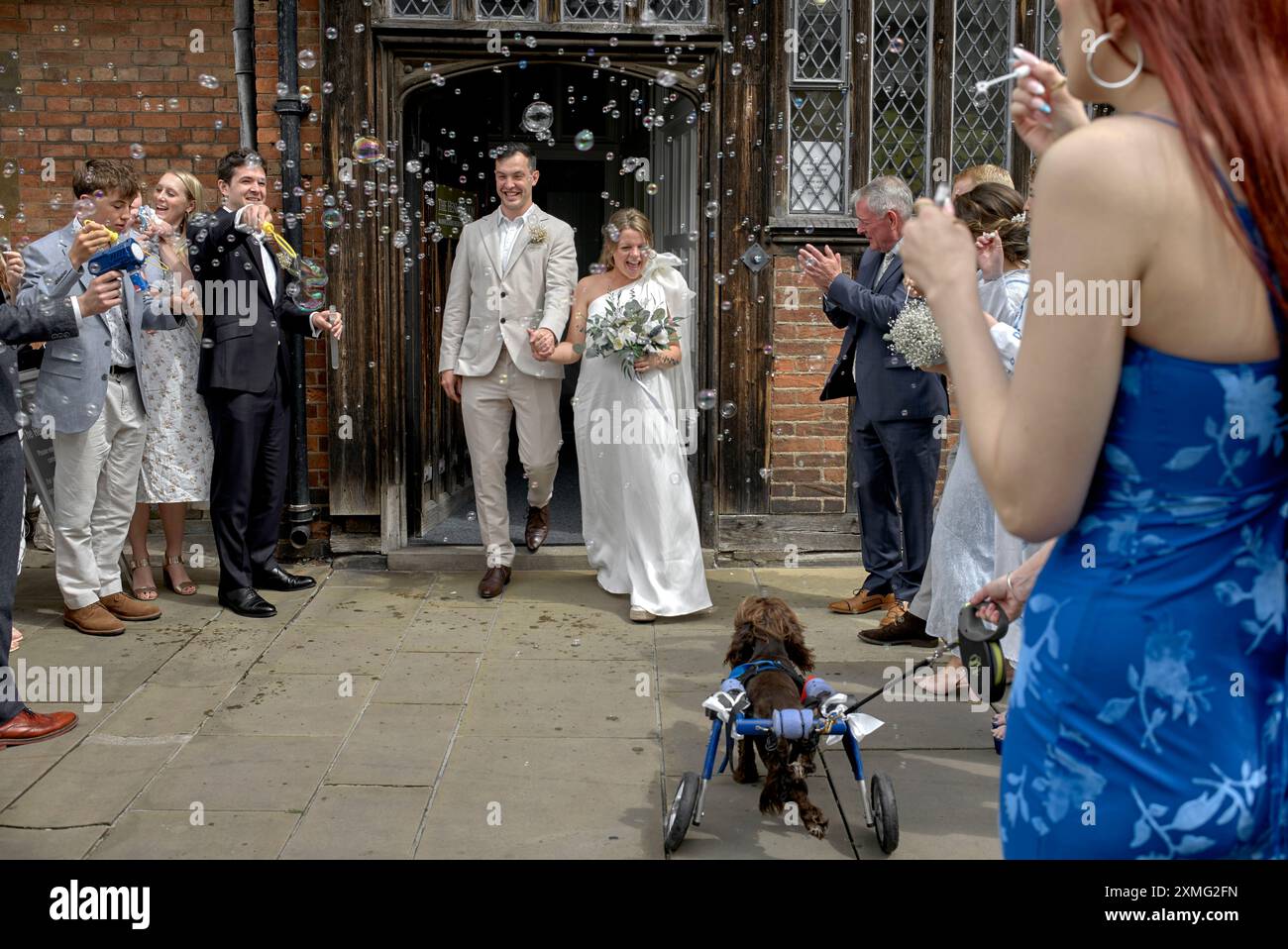 Wedding day bride and groom with guests blowing bubbles as they emerge ...